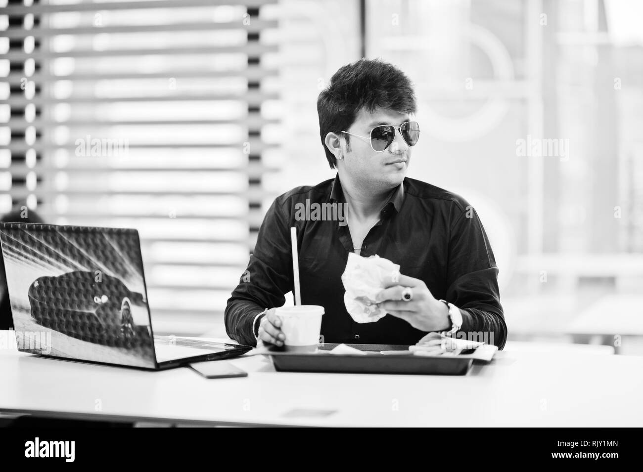 Stylish indian man in sunglasses sitting at fast food cafe against his ...
