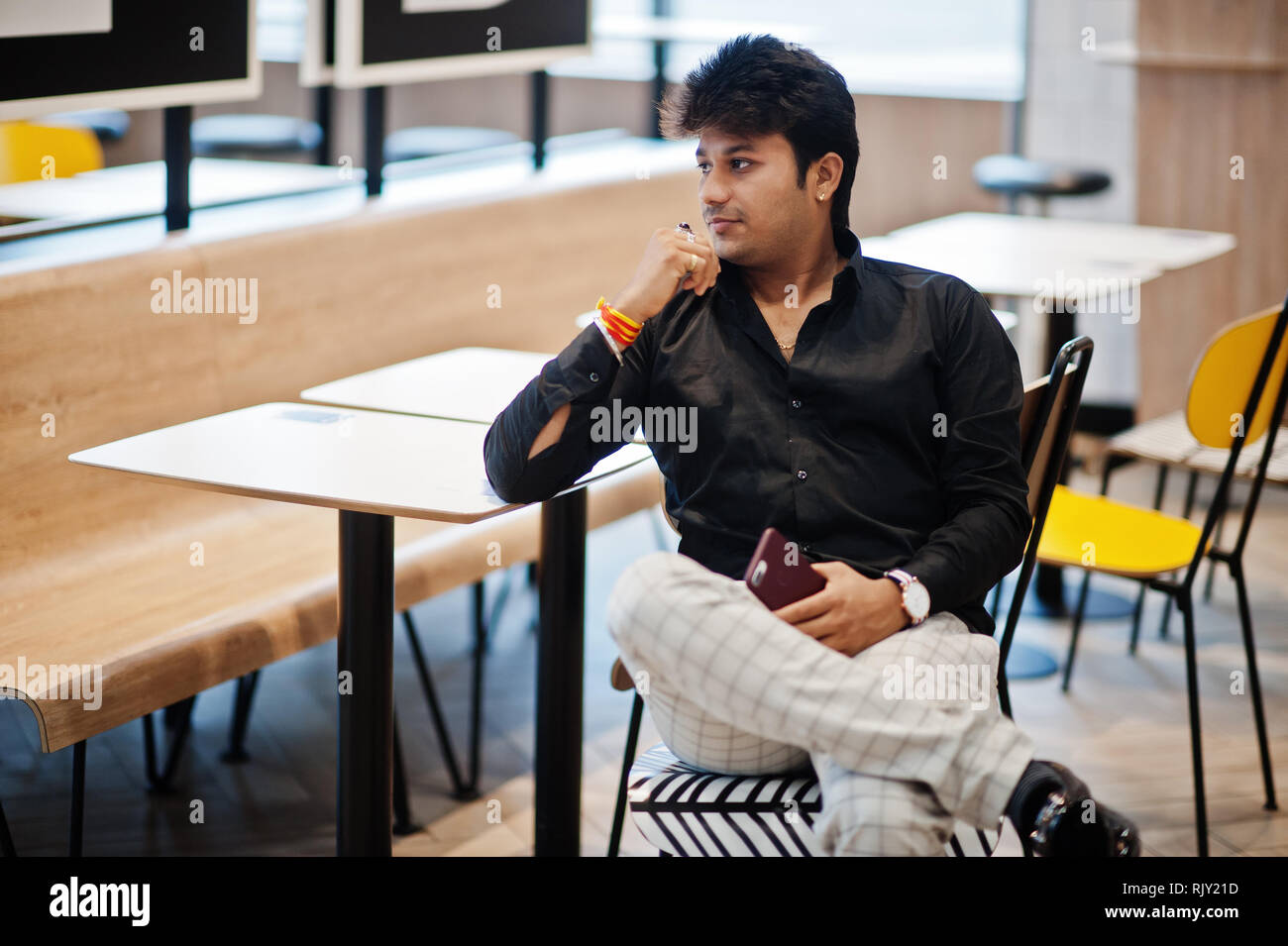 Stylish indian man sitting at fast food cafe and waiting his order ...