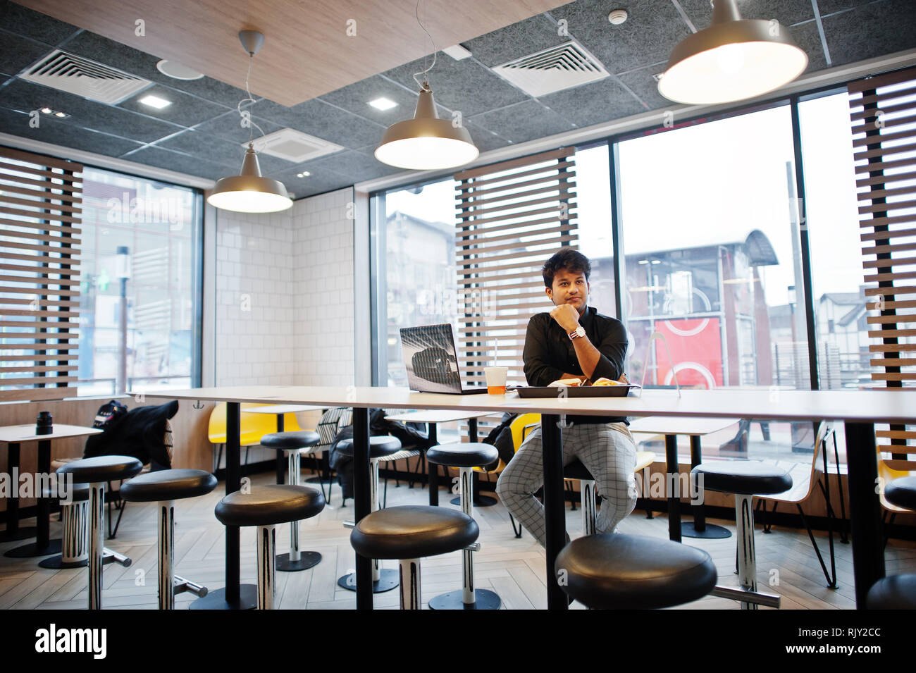 Stylish indian man sitting at fast food cafe against his laptop Stock ...