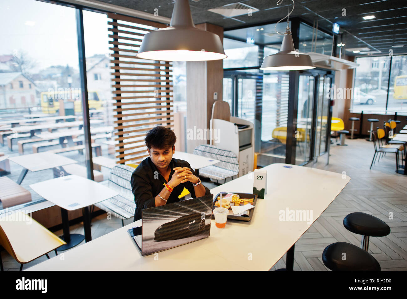 Stylish indian man sitting at fast food cafe against his laptop Stock ...