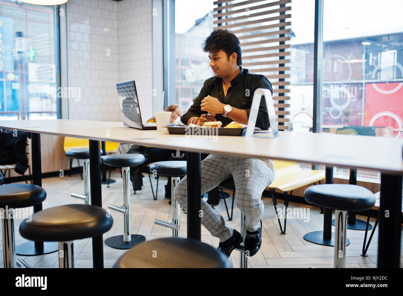 Stylish indian man sitting at fast food cafe against his laptop Stock ...