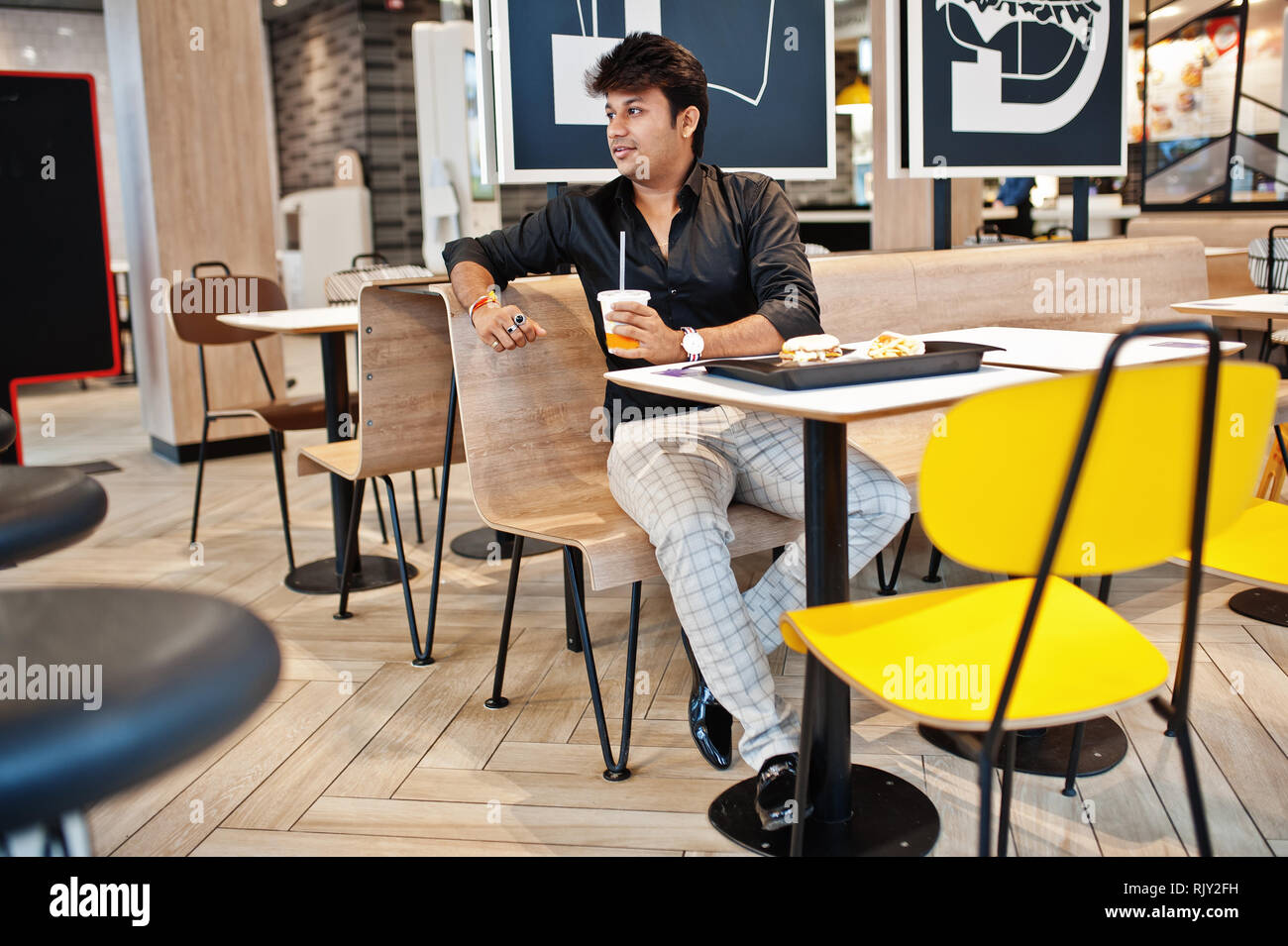 Stylish indian man sitting at fast food cafe and drink soda Stock Photo ...
