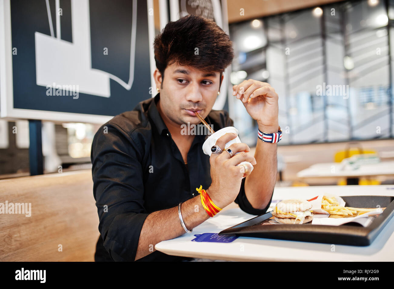 Stylish indian man sitting at fast food cafe and drink soda Stock Photo ...