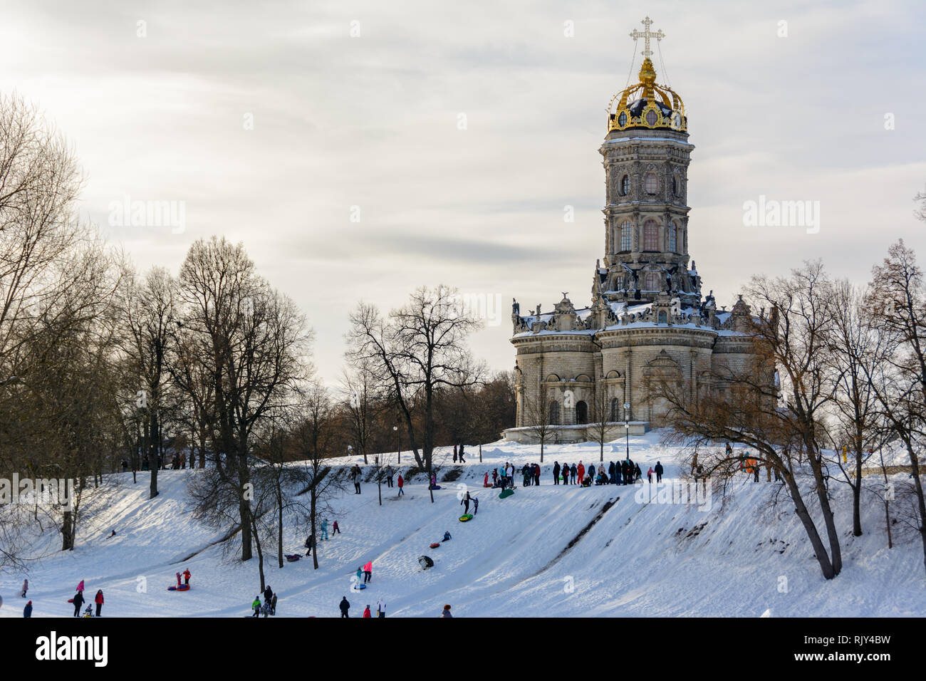 Children ride from the ice slide on a sunny winter day. Winter ...