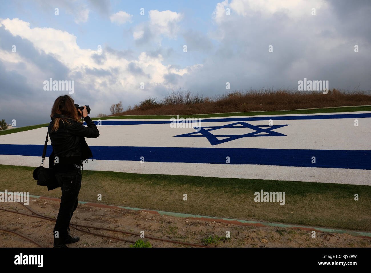A photojournalist photographing the Israeli flag made of painted lawn ...