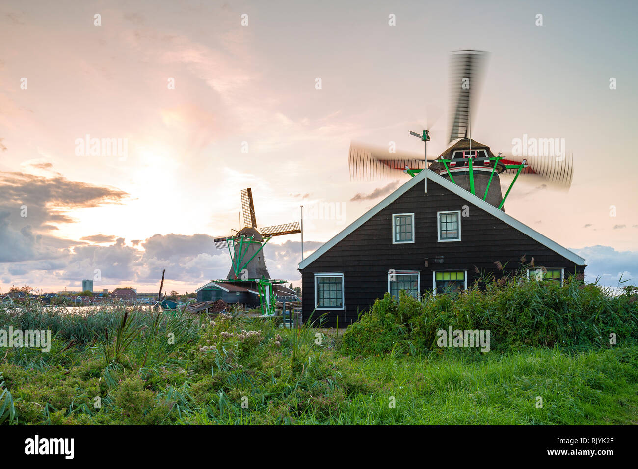 Traditional Dutch windmills near water at sunset, Zaanse Schans ...