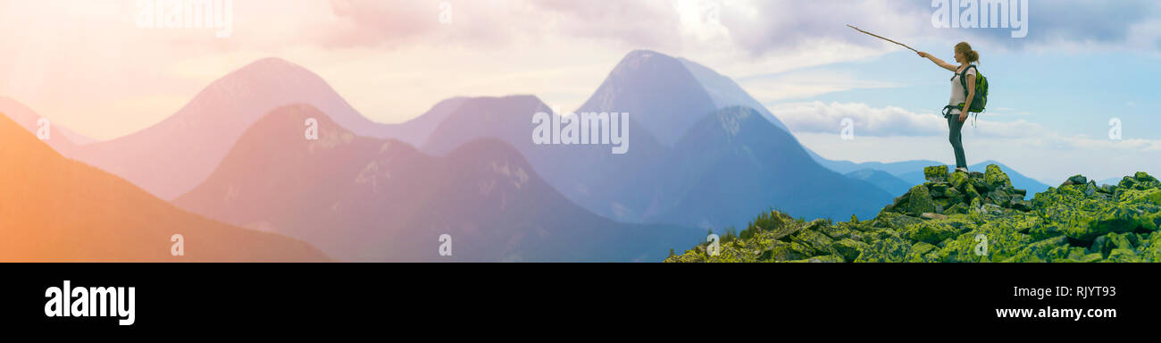 Young slim blond tourist girl with backpack points with stick at foggy ...