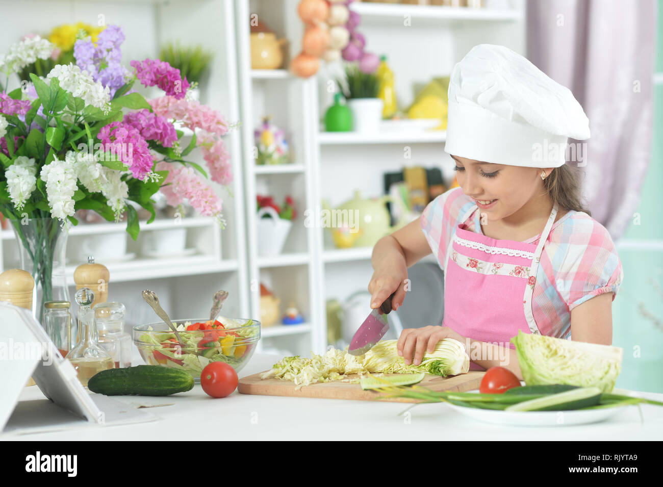 Cute little girl making dinner on kitchen table at home Stock Photo - Alamy