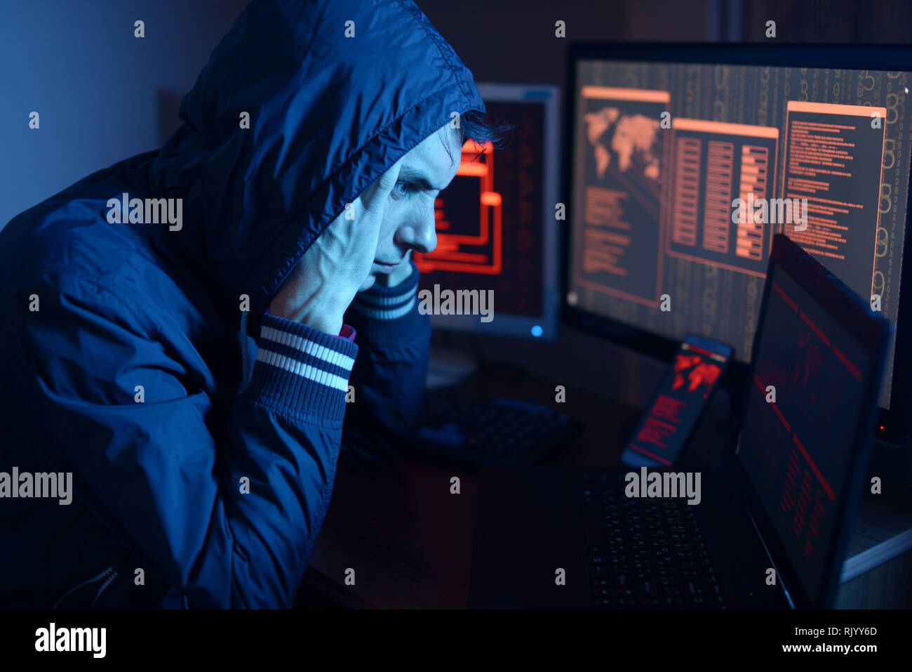 Hacker in a hood thinking about the problem of hacking or malware ...