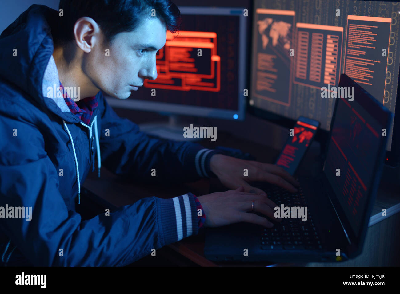 Hacker typing program code while committing a cybercrime hacking a ...