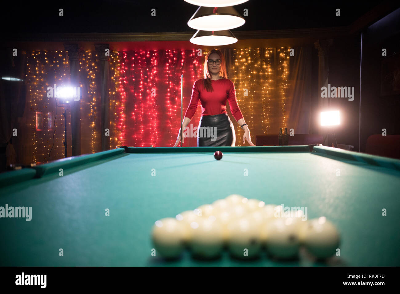 Billiard club. A woman with red hair and nice figure standing by the ...