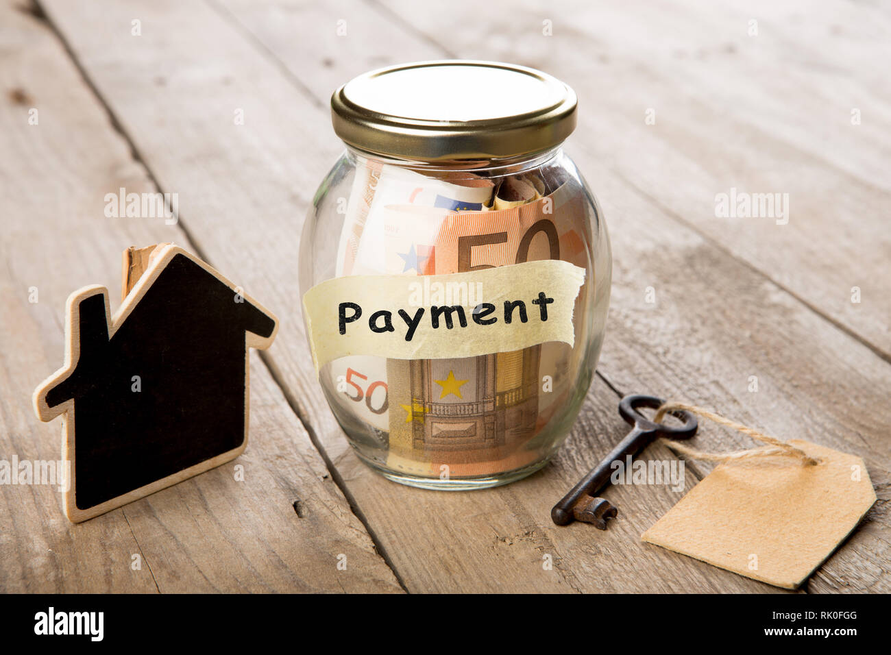 Rental payment concept - money jar, key with label and little house on ...