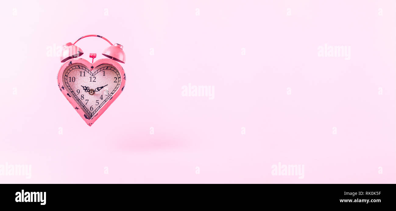 Heart shaped clock on pink background. Valentines day and love infitity ...