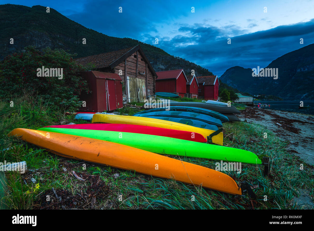 Row of upside down brightly coloured canoes by wooden huts and ...