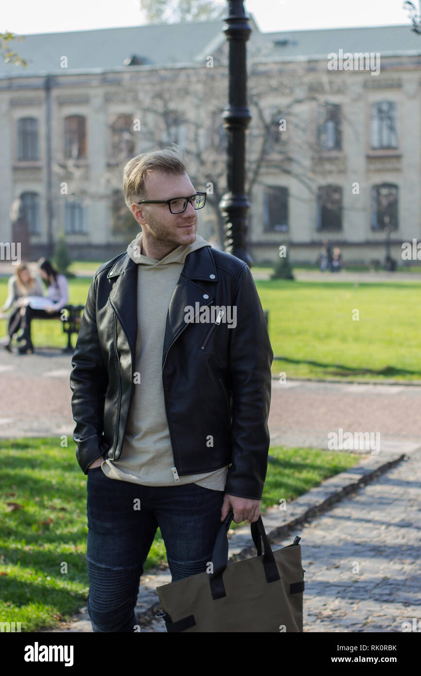 Smart smiling guy in casual clothes looking to the left, walks next to ...