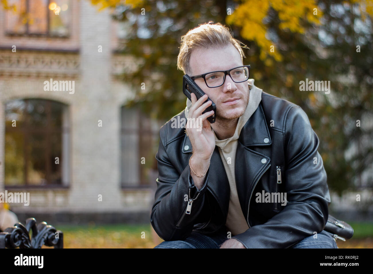 A dreaming smart guy in casual clothes is talking on the phone and is ...