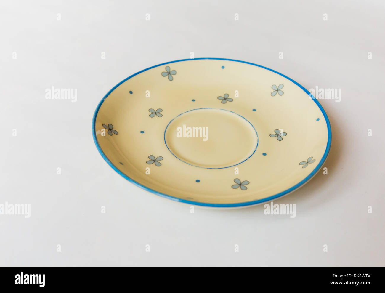 a yellow round plate with floral and line pattern on white background ...