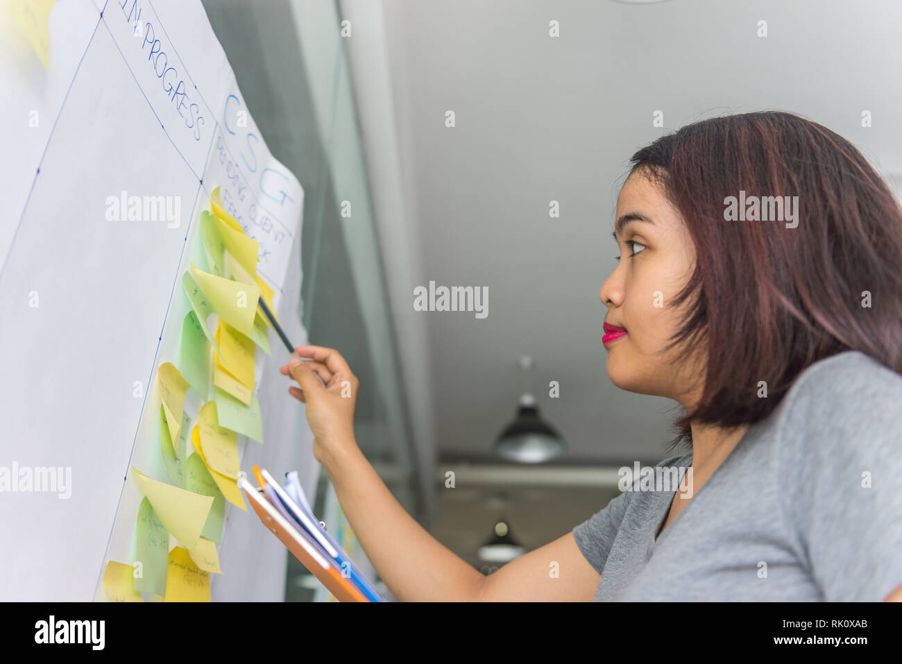 Young employee reading sticky notes on the board Stock Photo - Alamy