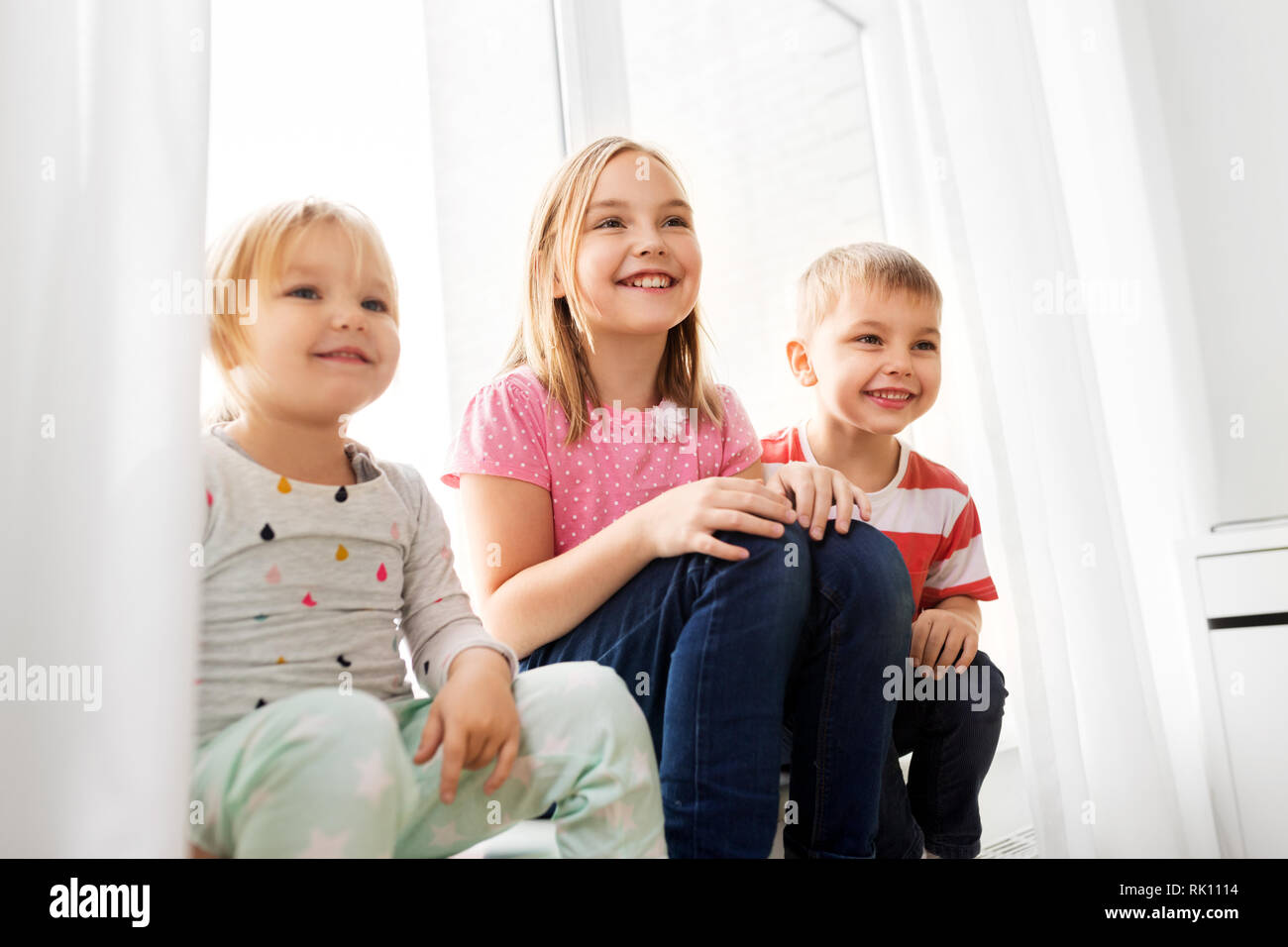happy little kids sitting on window sill Stock Photo - Alamy