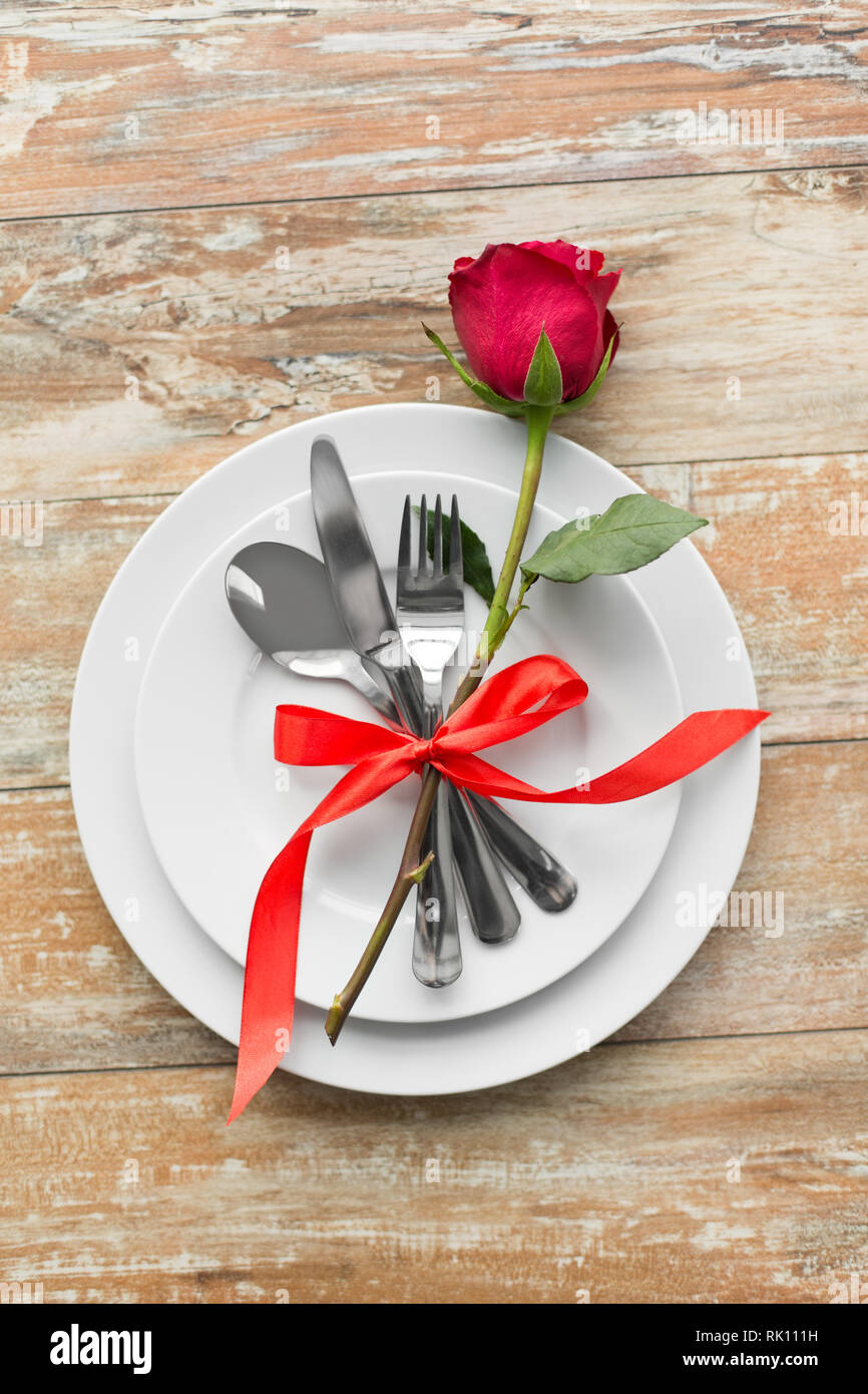red rose on set of dishes with cutlery on table Stock Photo - Alamy