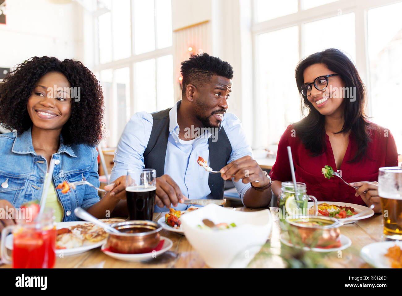 happy friends eating and talking at restaurant Stock Photo - Alamy