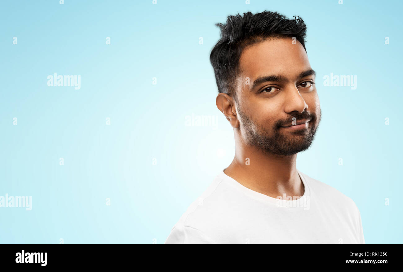 smiling young indian man over blue background Stock Photo - Alamy