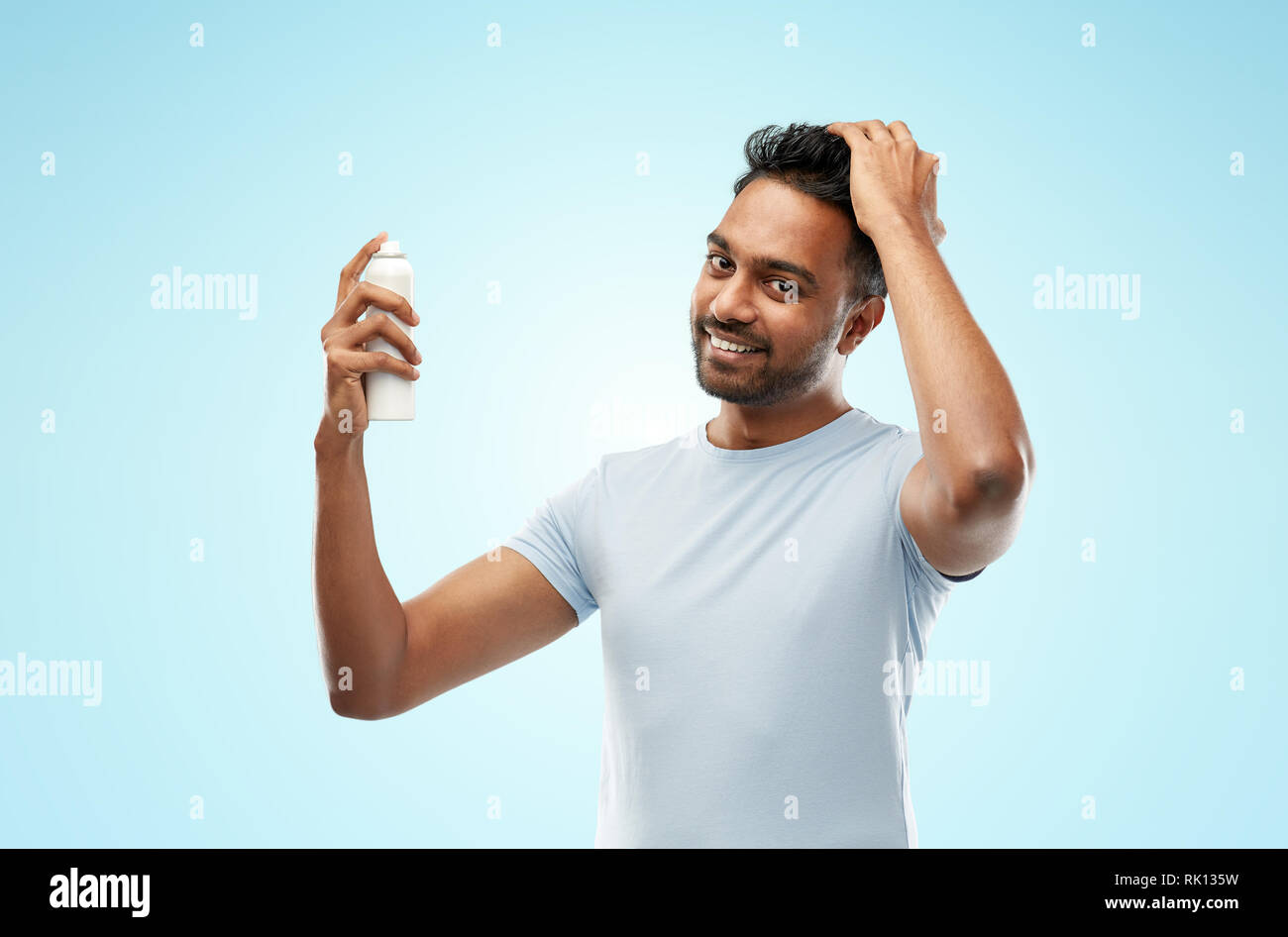 smiling indian man applying hair spray over blue Stock Photo - Alamy