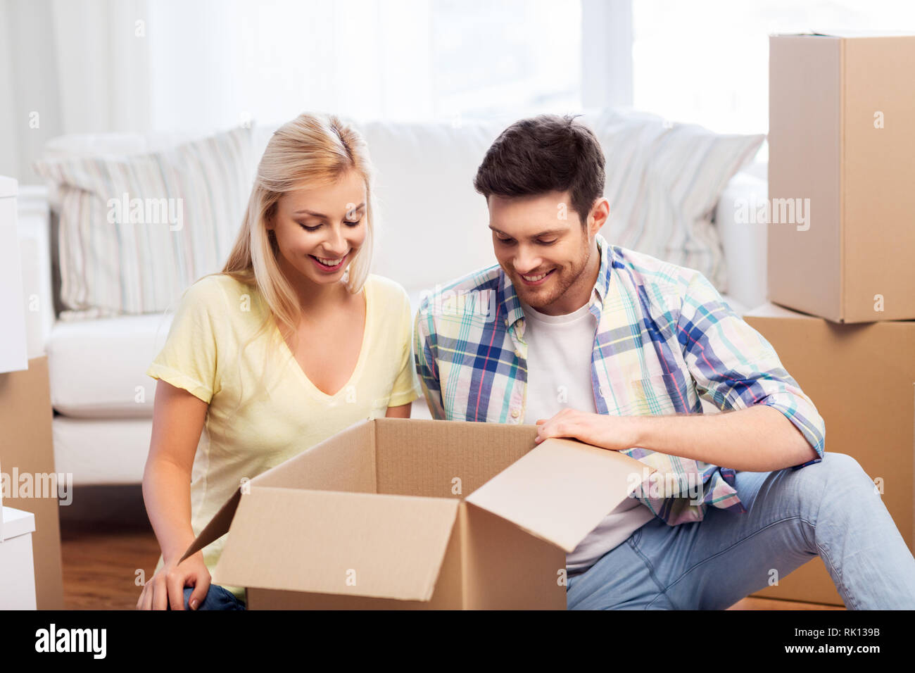 happy couple unpacking boxes at new home Stock Photo - Alamy