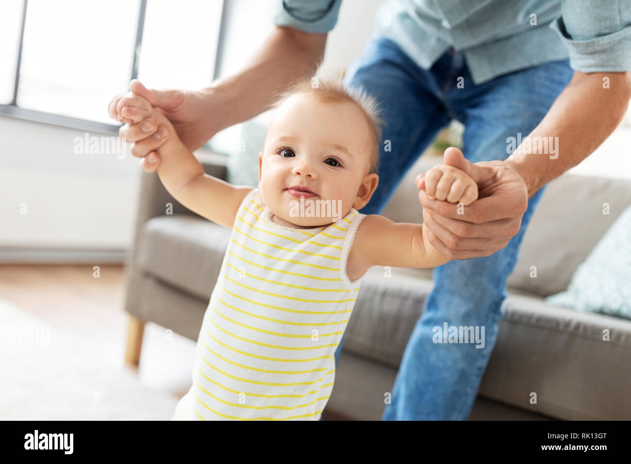 father helping baby daughter with walking at home Stock Photo - Alamy