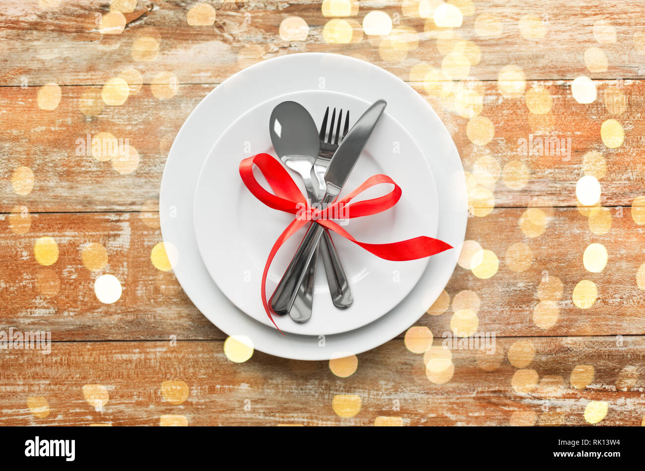 cutlery tied with red ribbon on set of plates Stock Photo - Alamy
