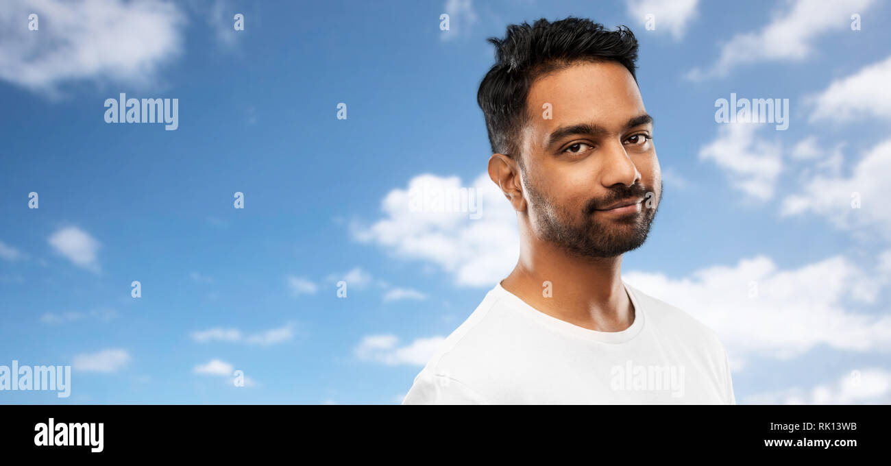 smiling young indian man over blue sky background Stock Photo - Alamy