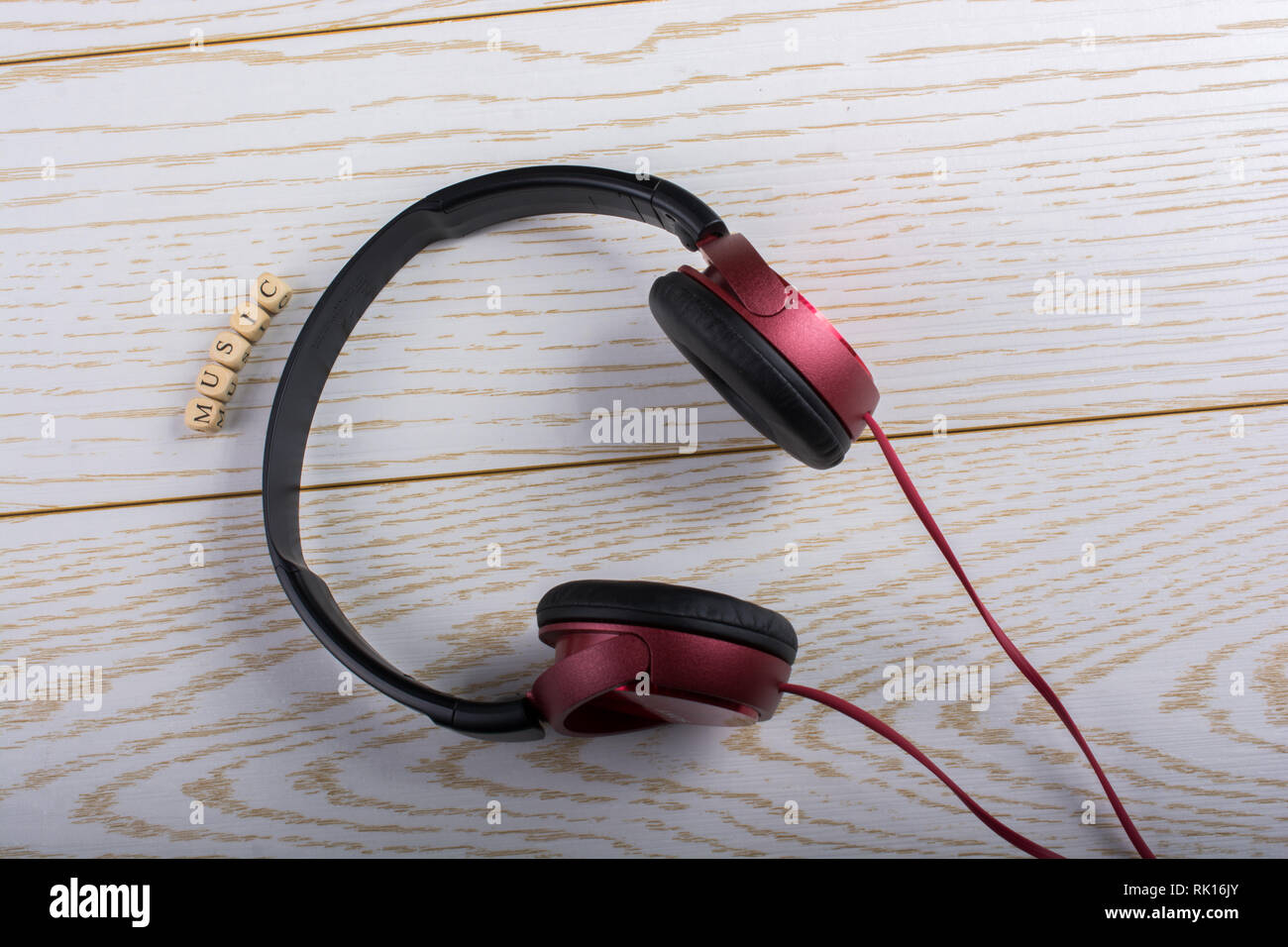 Dice-sized alphabet cubes spelling music and red headphones on wooden ...