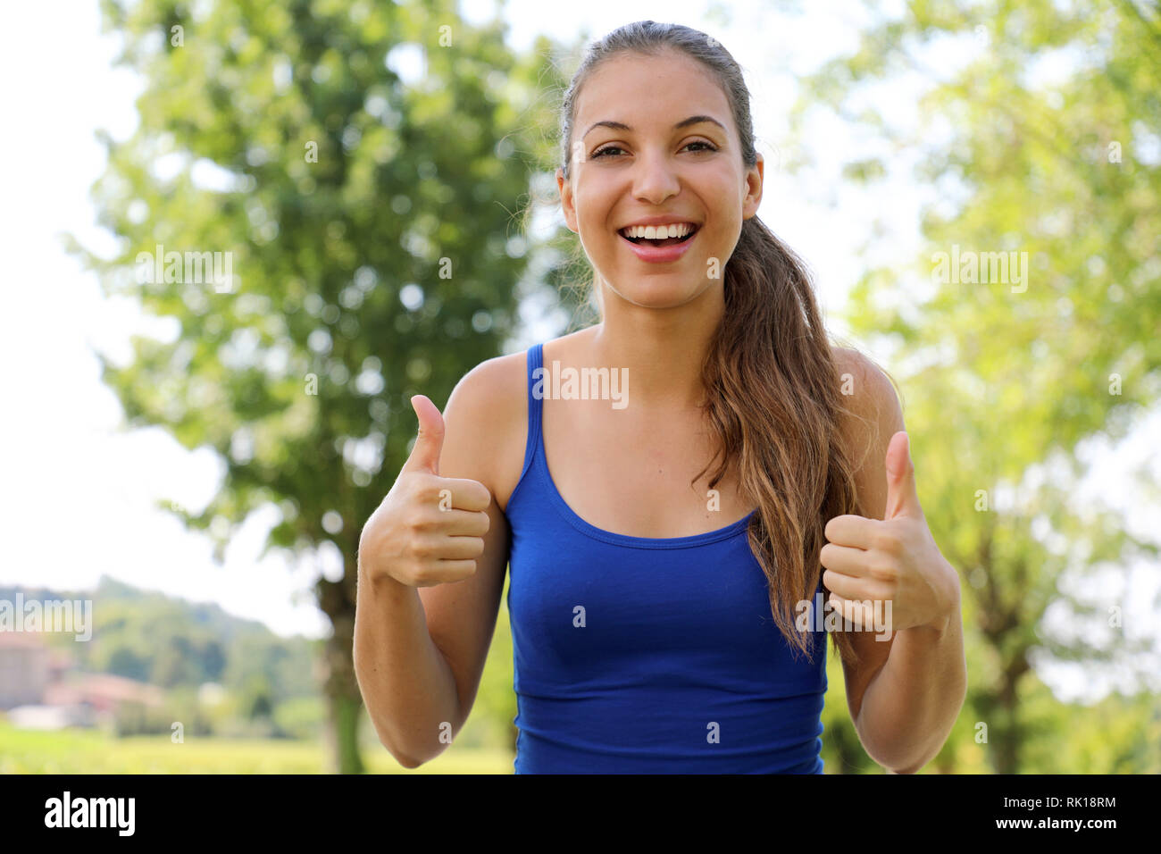 Portrait of winning girl showing thumbs up. Positive smiling fitness ...