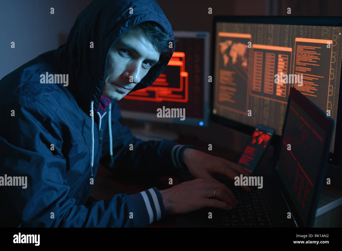 Male in the hood looking in the camera. Hacker attacks and online fraud ...