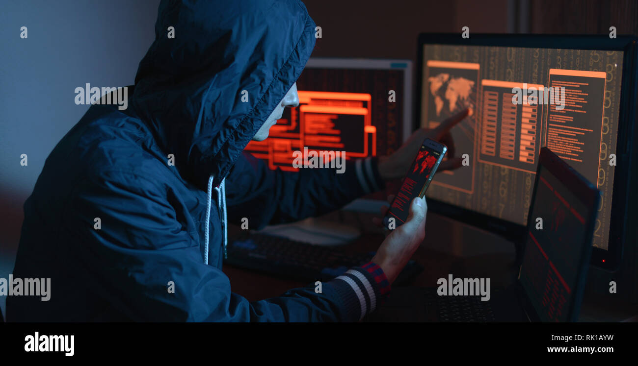 The male hacker in the hood is pointing his finger at the display ...