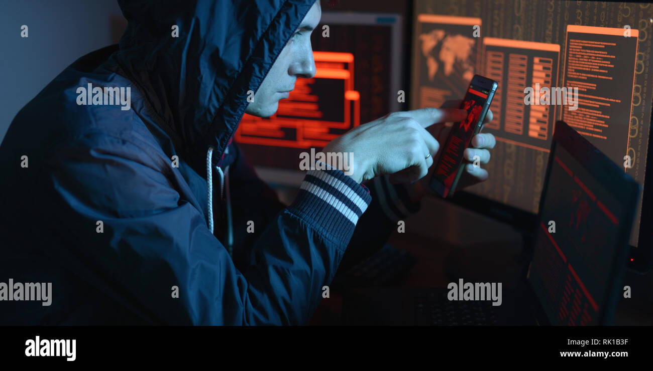 The male hacker in the hood is pointing his finger at the display ...