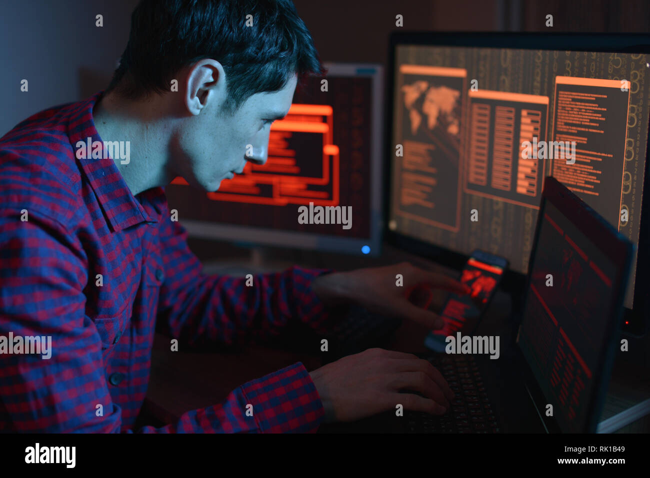 The male hacker in the hood is pointing his finger at the display ...
