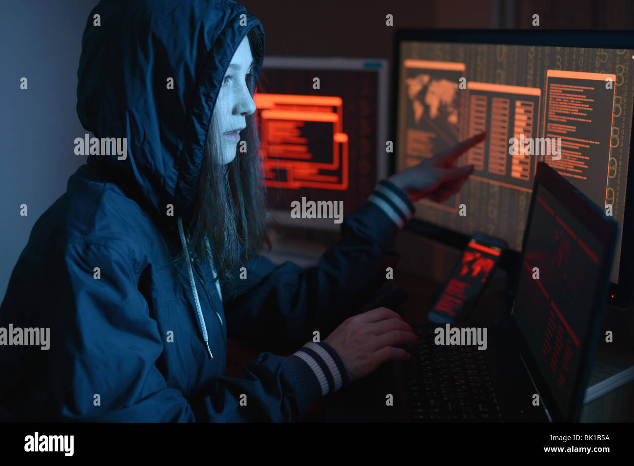 Girl hacker is pointing her finger at the display indicating the ...