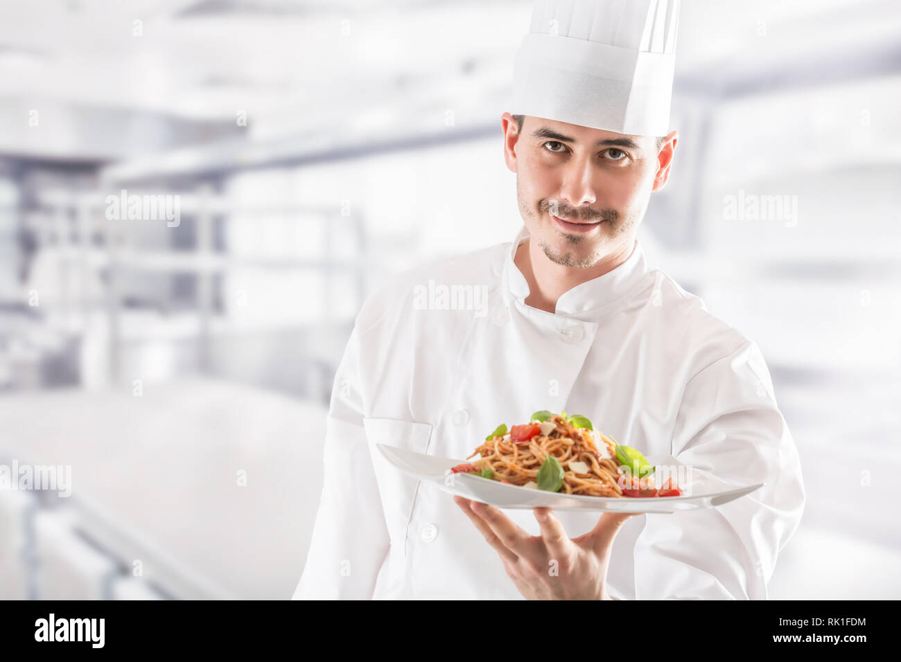 Chef in restaurant kitchen holding plate with italian meal spaghetti ...