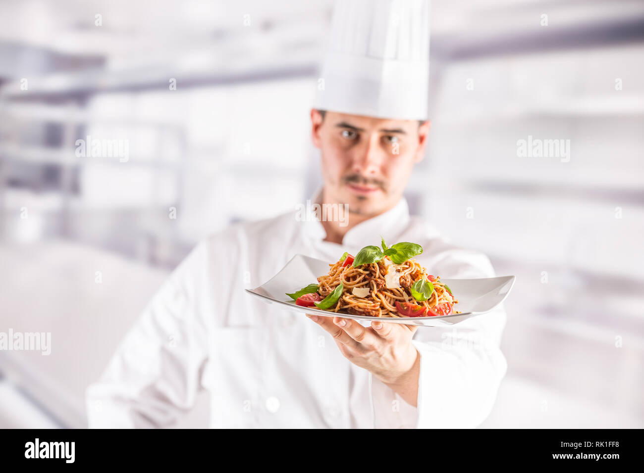 Chef in restaurant kitchen holding plate with italian meal spaghetti ...