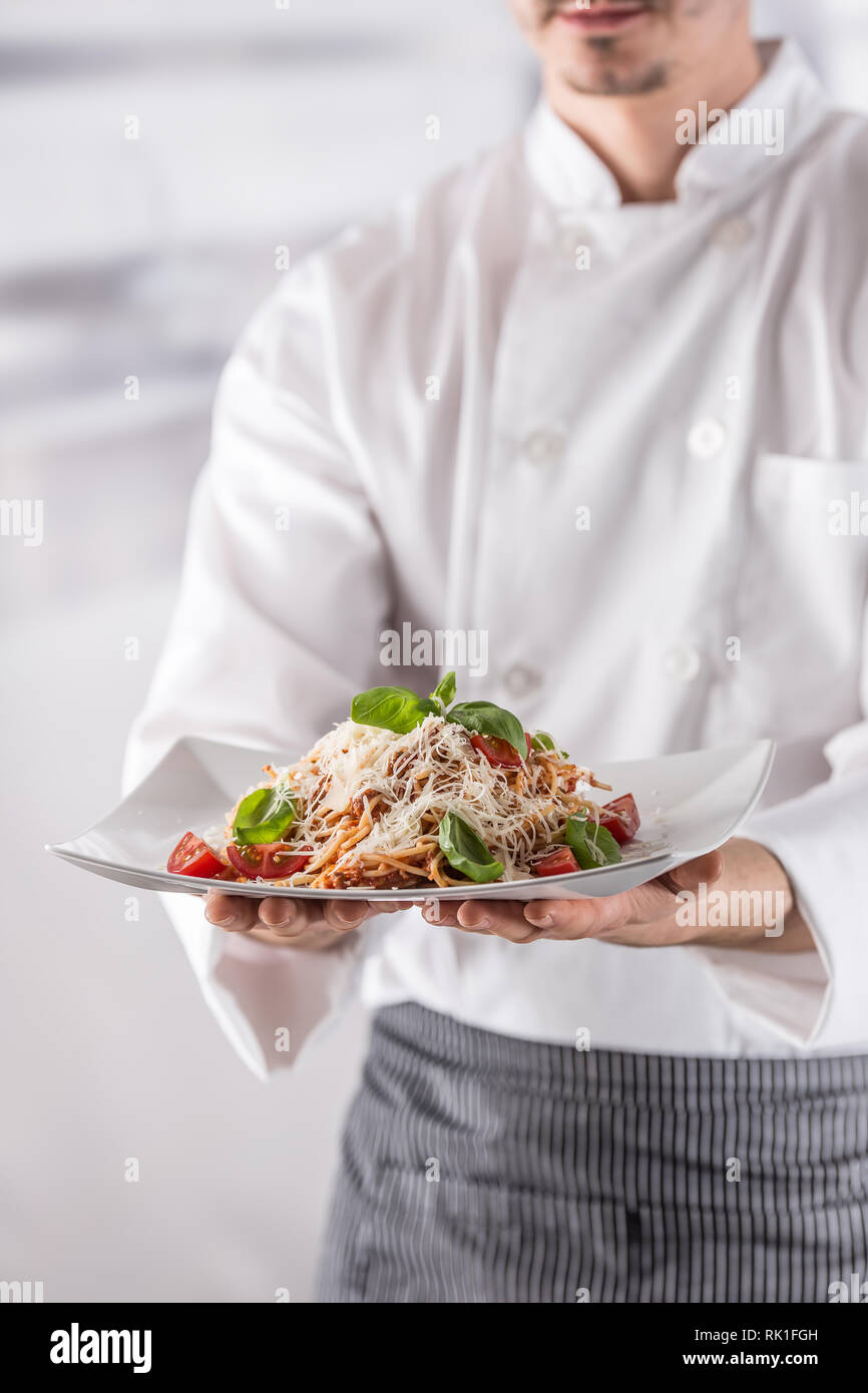 Chef in restaurant kitchen holding plate with italian meal spaghetti ...
