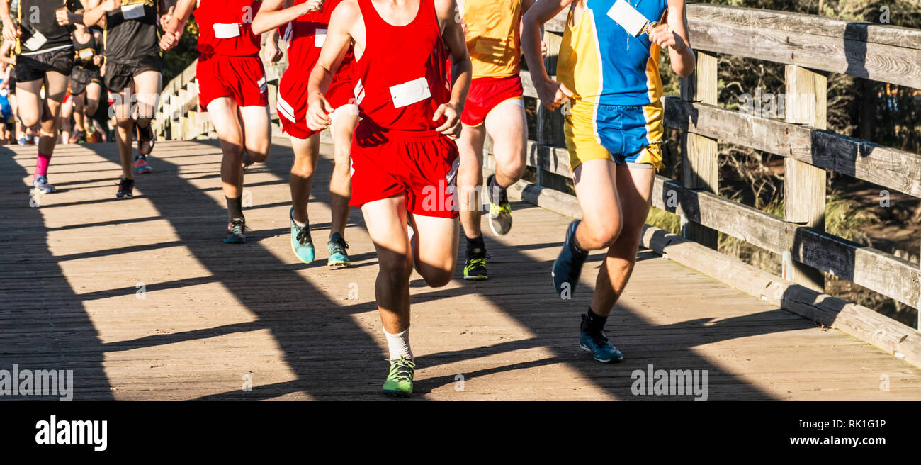 High school boys cross country race running over a wooden bridge at ...