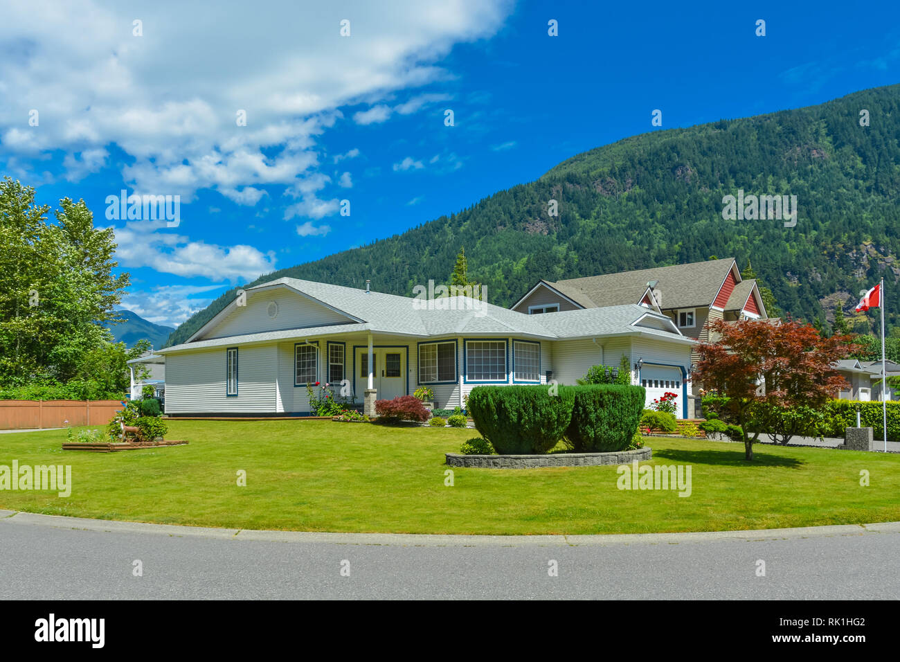 One level rancho house with Canadian flag on a front yard on blue sky ...