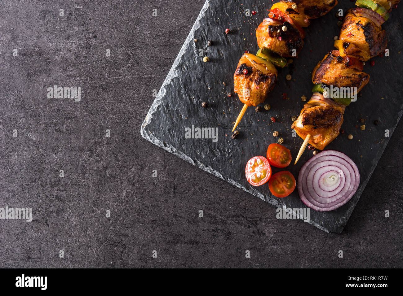 Chicken shish kebab with vegetables on black stone. Top view. Copyspace ...