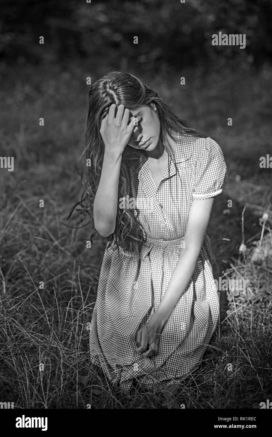 Young girl in vintage dress sitting on grass. Brunette covering her ...