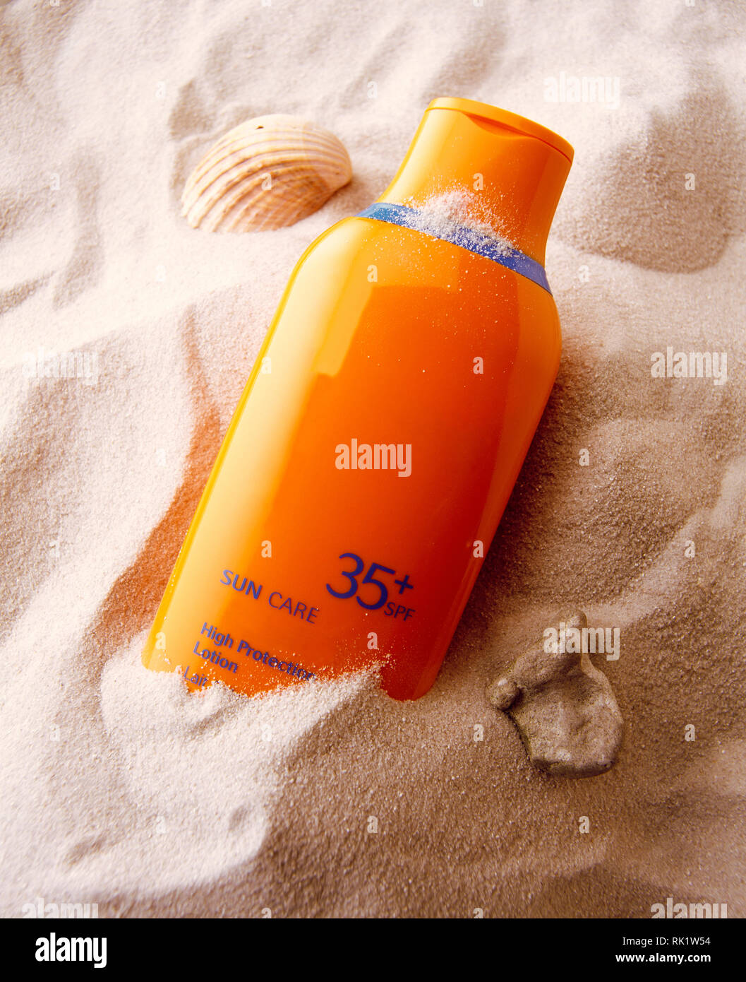 Bottle of sun screen isolated on sand at the beach with copy space ...