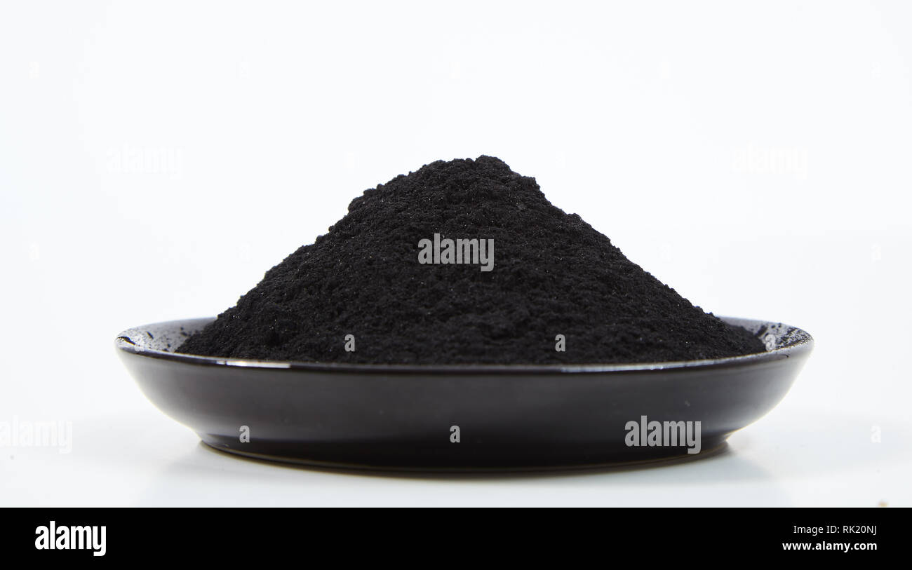 A pile of powdered charcoal on black plate, viewed from the side ...
