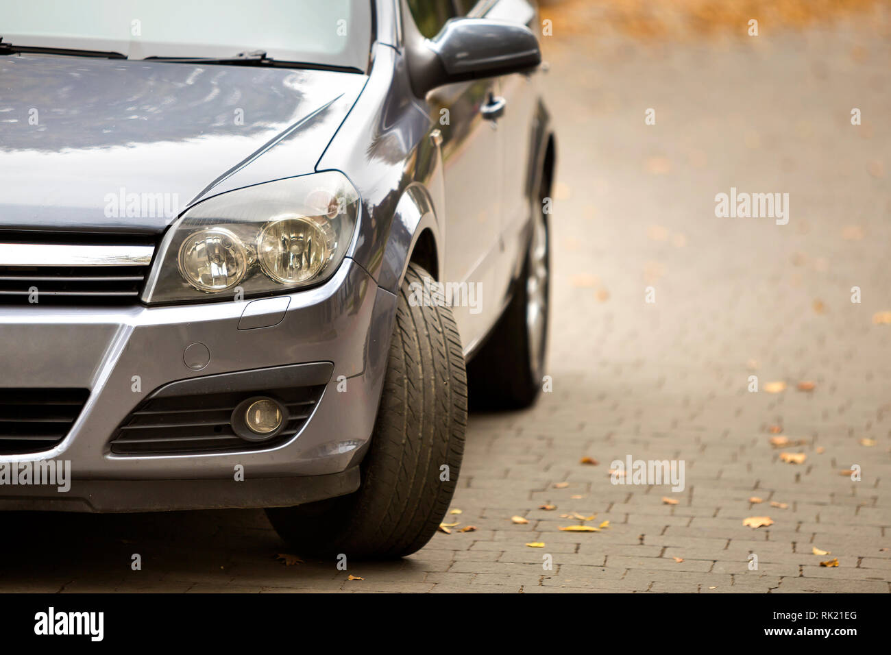 Gray shiny car parked in quiet area on asphalt road on blurred bokeh ...