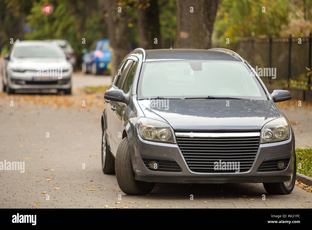 Gray shiny car parked in quiet area on asphalt road on blurred bokeh ...