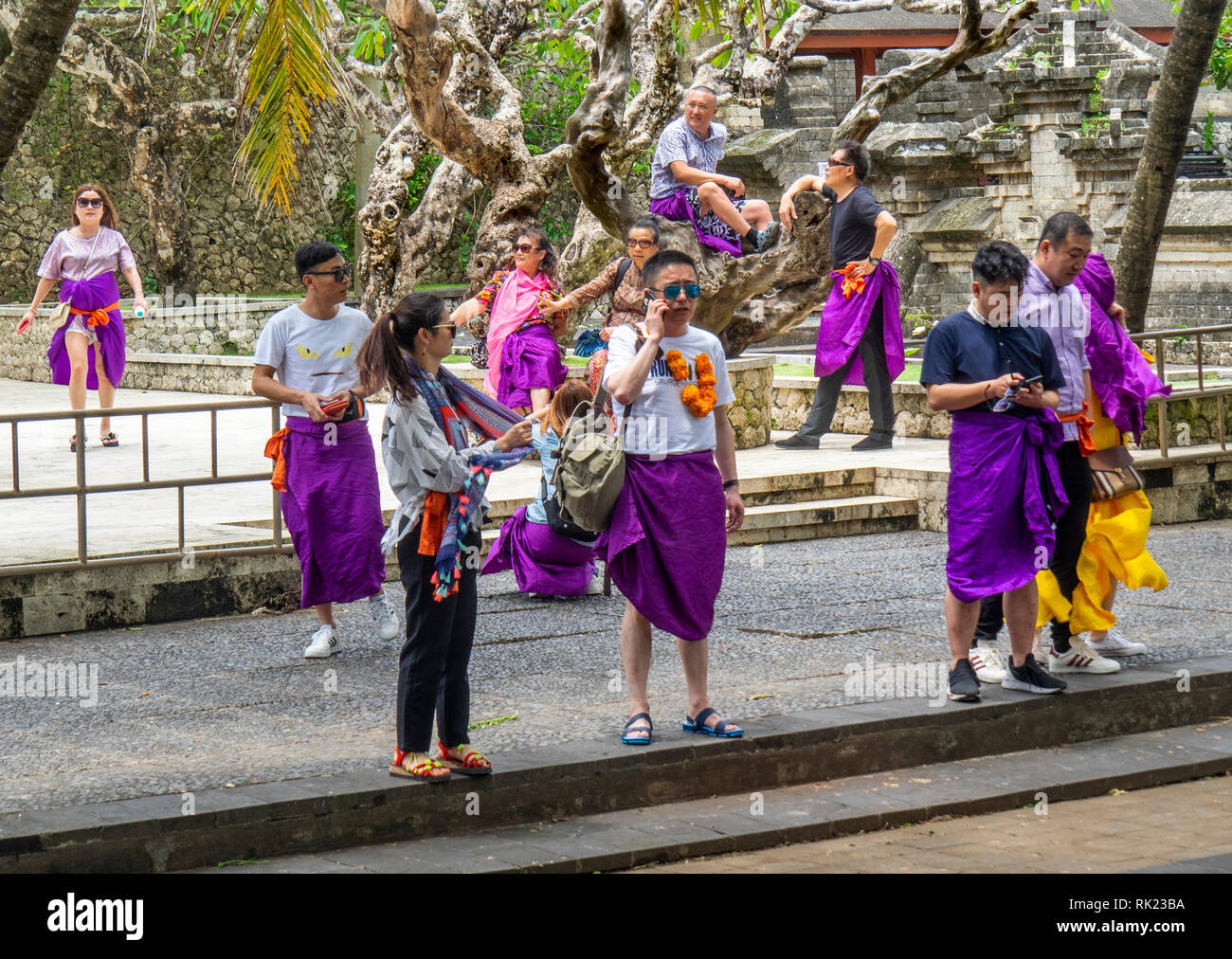 Chinese tourists wearing purple sarongs visiting Uluwatu Temple Bali ...